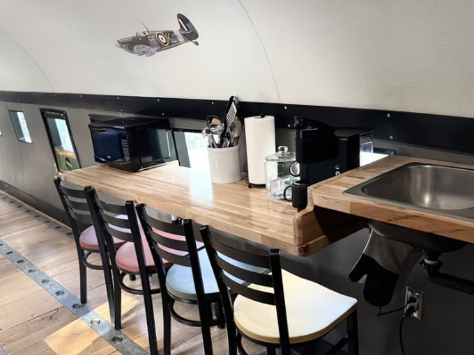Inside the transformed fuselage, a cozy dining area with wooden countertops offers surprising comfort in this airborne abode.