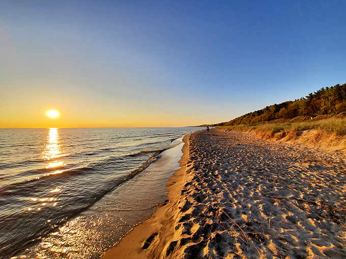 The sun bids farewell in spectacular fashion, painting the sky in warm hues while a lone kayaker witnesses the magic.