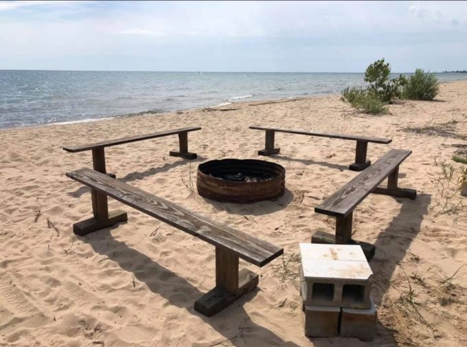 Simple pleasures: wooden benches surround a fire pit where stories and s'mores are shared under starry Michigan skies.