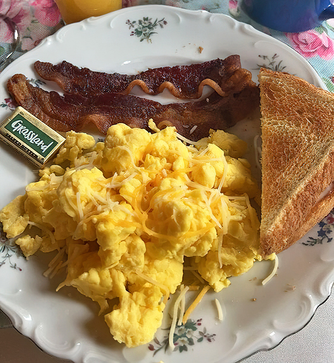 Fluffy scrambled eggs with melted cheese and perfectly crisp bacon, breakfast that makes morning people out of night owls.