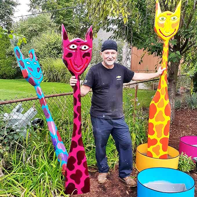 The artist stands proudly with his giraffe-like creations, each one a towering testament to imagination's power to transform discarded materials.