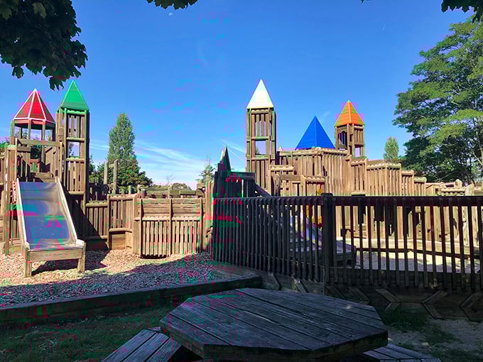 Fort-like wooden structures with colorful turrets create a playground paradise where imagination runs wild at Lighthouse Park.