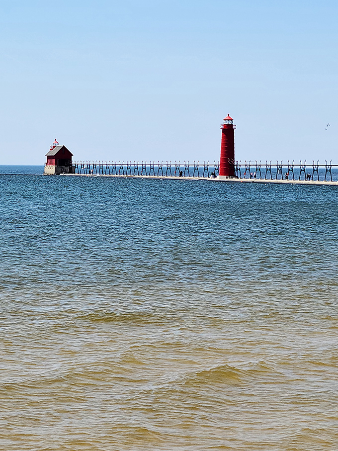 The pier stretches toward the horizon like a runway to adventure, connecting the charming shoreline to Grand Haven's famous red lighthouse.