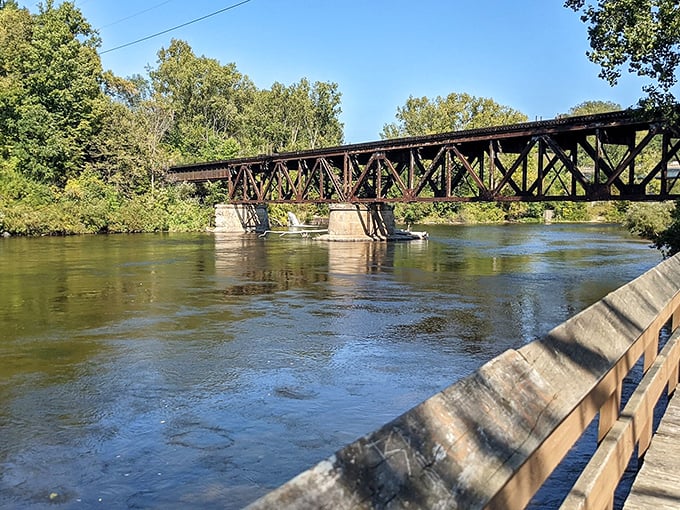 The historic railroad bridge spans the Muskegon River like an iron sentinel, connecting past and present while offering spectacular views of the flowing waters below.