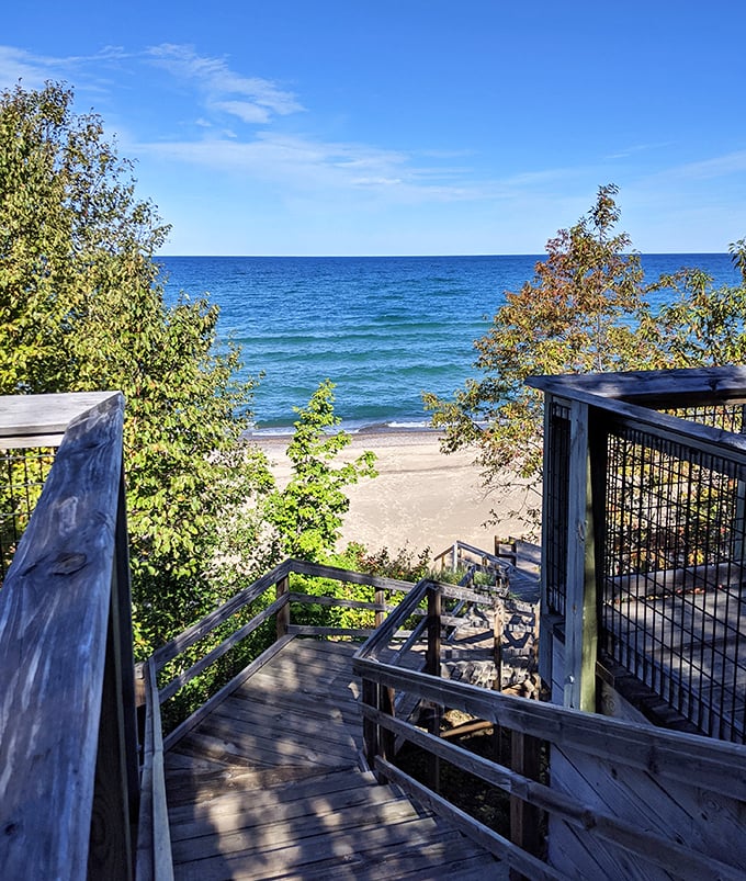 Wooden steps descend to paradise, offering glimpses of turquoise waters between weathered railings and whispering pines.