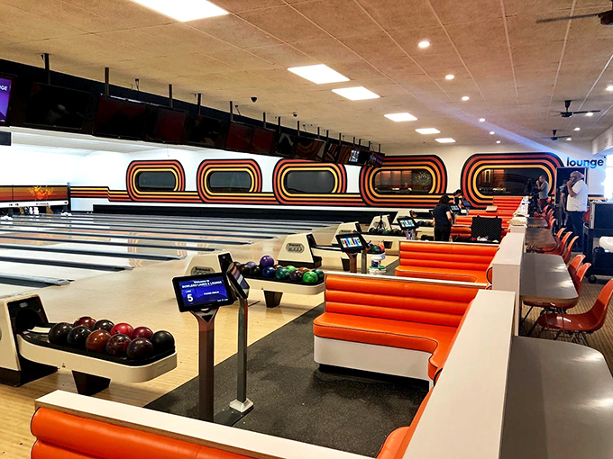 Orange seating curves alongside pristine lanes, creating retro comfort stations between turns at this bowling time capsule.