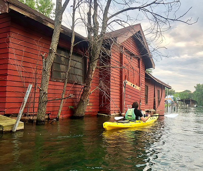 A paddler explores the weathered charm of canal-side structures, where history and nature create a uniquely Detroit waterfront experience.