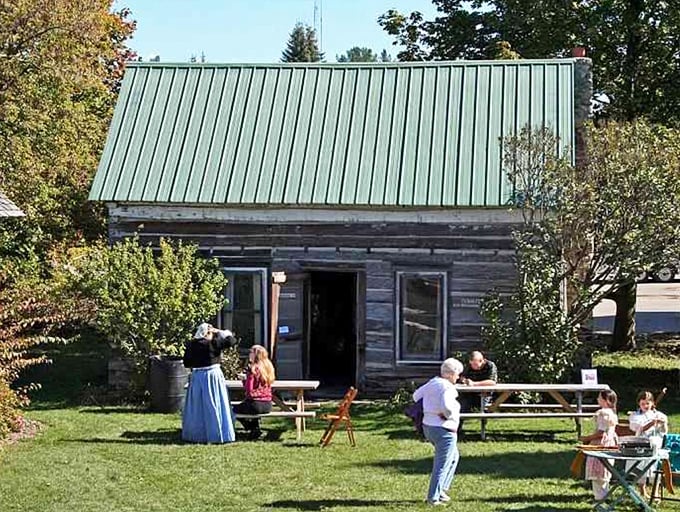 Visitors gather outside a historic log cabin, experiencing firsthand how Michigan pioneers made the most of limited space and resources.