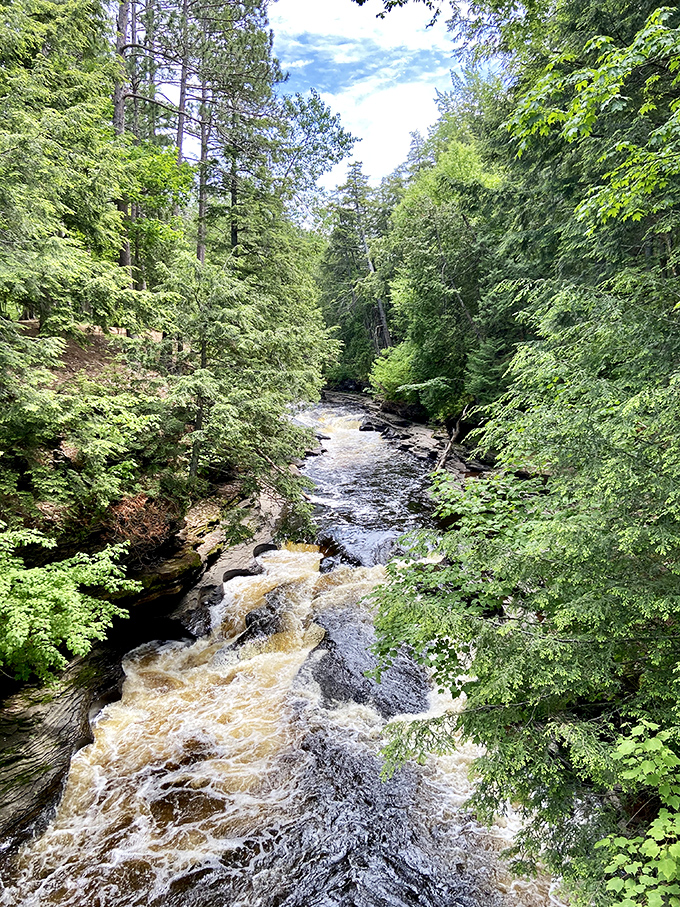 The Presque Isle River carves its amber path through millennia-old stone, telling Earth's story one ripple at a time.