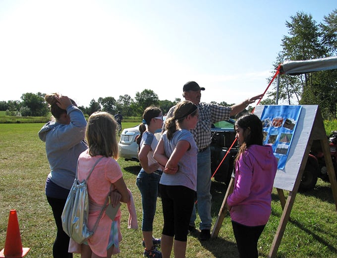 Curious visitors gather around a guide, soaking up sunflower wisdom while surrounded by towering yellow blooms.