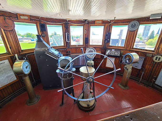The wheelhouse remains frozen in time, its vintage navigation equipment and massive wheel waiting for phantom hands to guide this iron giant through imaginary waters.