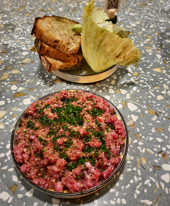 This beef tartare isn't just food&mdash;it's a tiny masterpiece, with each ruby-red morsel hand-cut to perfection and topped with fresh herbs.