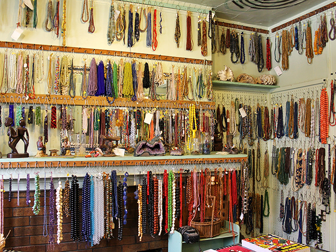 Rainbow rivers of beads cascade along the walls, each strand telling stories of trade routes, cultural significance, and artistic traditions spanning continents.