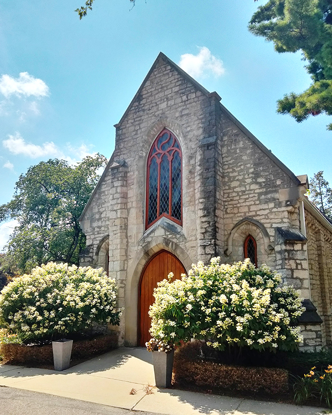 Elmwood's stone chapel blooms with life, flanked by vibrant hydrangeas that soften the solemnity of this sacred space.