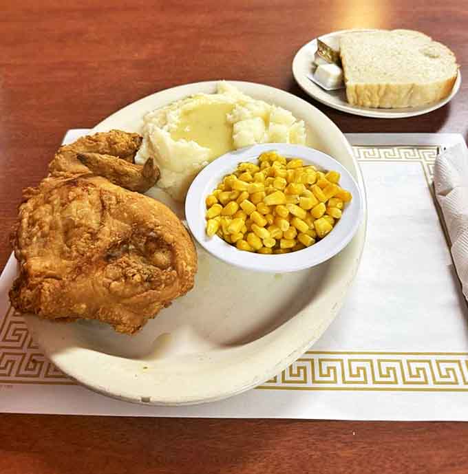 Golden-brown perfection on a plate: crispy exterior giving way to juicy meat, alongside creamy mashed potatoes and sweet corn.