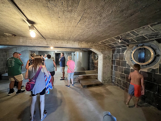 Visitors explore the lighthouse's interior service room, where history whispers from concrete walls that have weathered a century of storms.