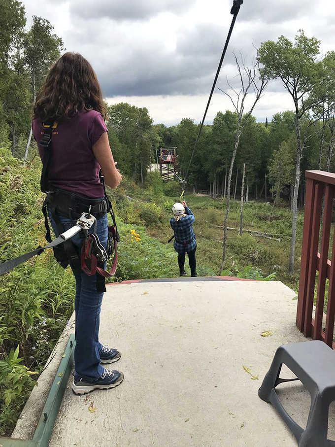 Thrill-seekers prepare for an exhilarating zipline adventure, soaring above Michigan's lush forest canopy with equal parts terror and delight.