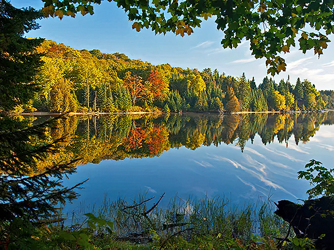 Mirror-like waters reflect autumn's fiery palette, creating a double dose of visual magic for lucky visitors.