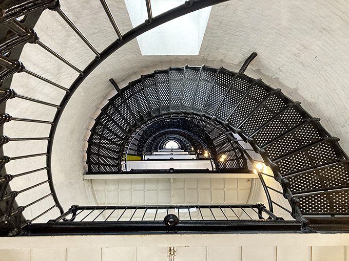 Dizzying spiral staircase winds 219 steps to the top—each metal step worn by keepers, tourists, and perhaps a phantom footfall or two.