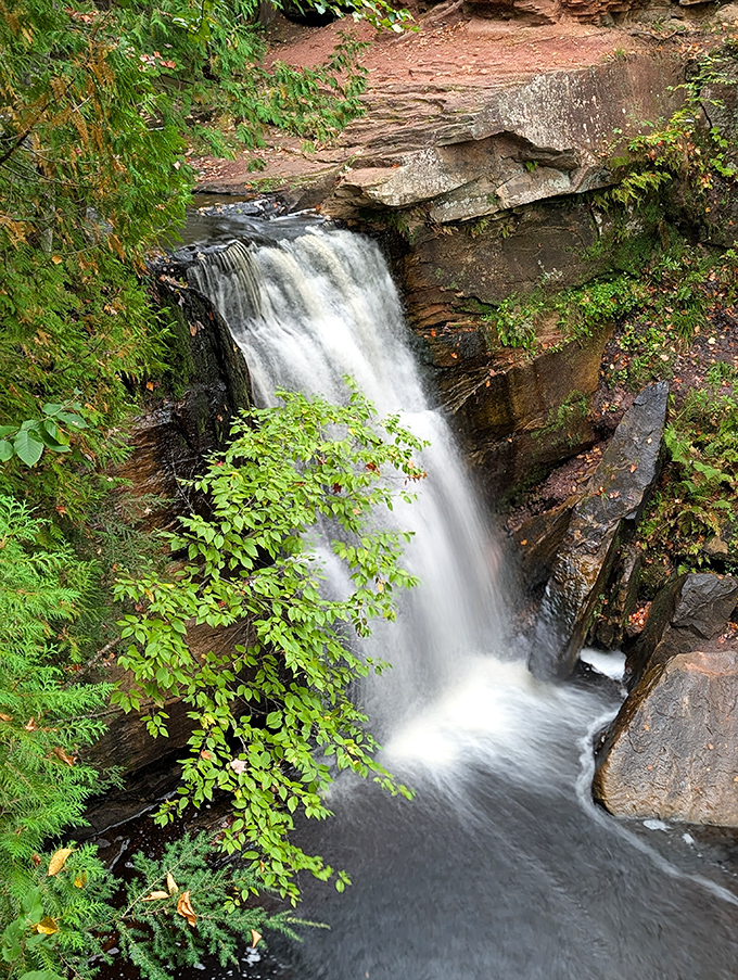 Nature's perfect viewpoint reveals layers of rock and vegetation, framing this waterfall in a portrait worthy of a master painter.