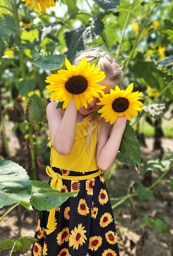 Peek-a-boo perfection! A young visitor finds the most creative way to frame that beautiful face among nature's most cheerful blooms.