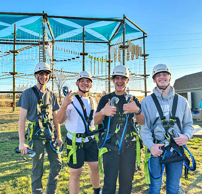 Safety first, fun second! These adventure-seekers are properly equipped for the ropes course, though their expressions suggest they're reconsidering their bravado.