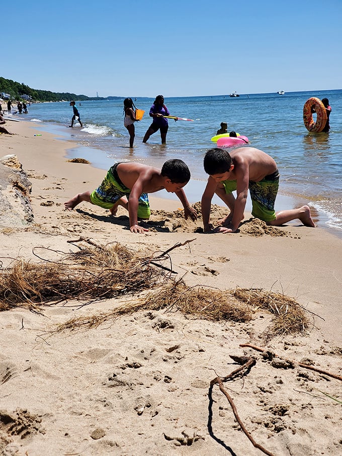 Young architects of sand construct their temporary masterpieces while beachgoers soak up Michigan's summer sunshine, creating memories that outlast their castles.