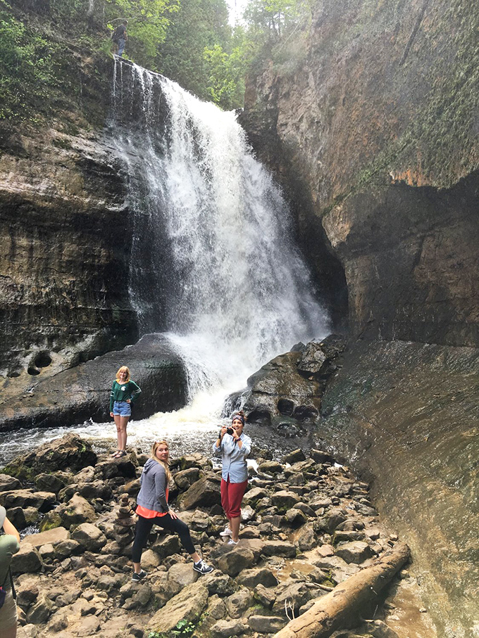 The universal pose of waterfall appreciation, where standing on rocks and looking up is somehow both dangerous and irresistible.