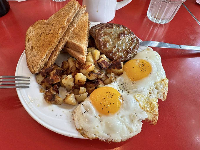 Breakfast perfection on a plate: sunny-side-up eggs with that ideal runny yolk, crispy-edged breakfast meat, and home fries that could make a potato weep with joy.