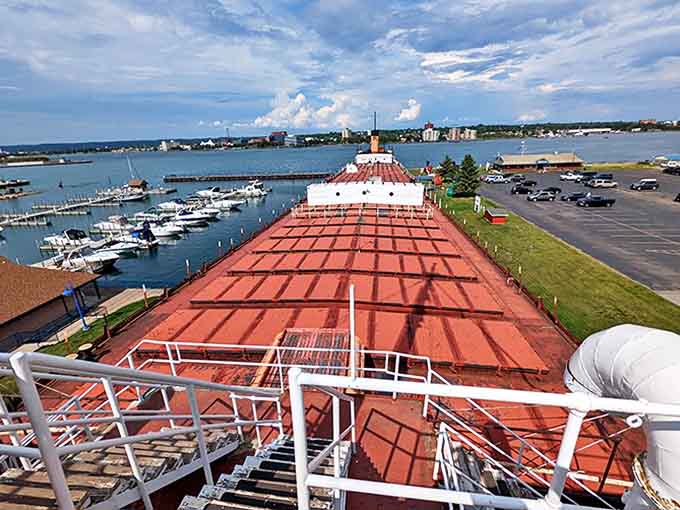 From the deck, visitors gain perspective on the massive scale of this former freighter. The red cargo hatches stretch toward the horizon like a floating runway.
