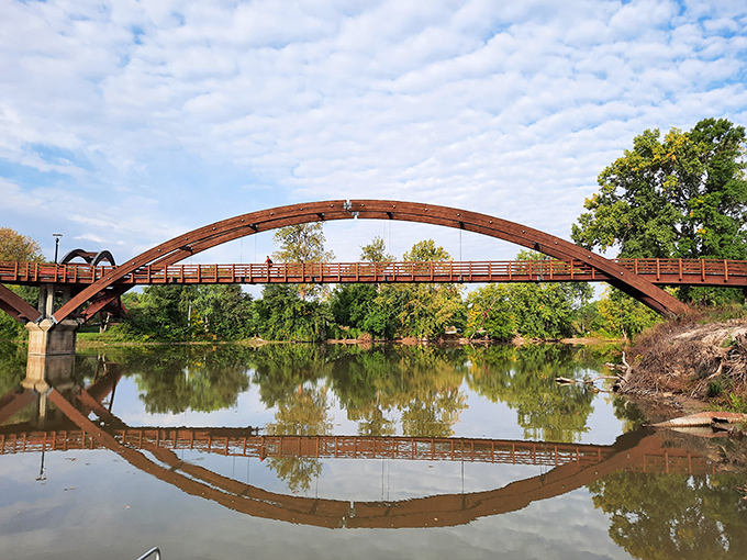 Mirror-like waters double the visual impact, creating a perfect circle where wooden arches meet their reflections in a mesmerizing optical illusion.