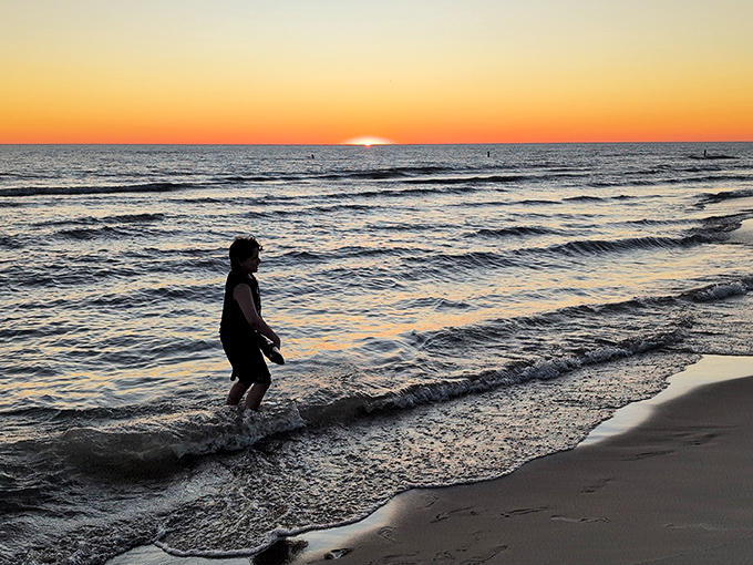 That magical moment when day surrenders to evening, painting Lake Michigan's waters with liquid gold that makes everyone pause in wonder.