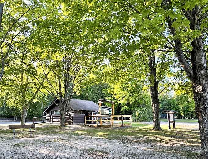 The rustic visitor center blends perfectly with its natural surroundings, sheltered by towering maples that have witnessed decades of happy campers.