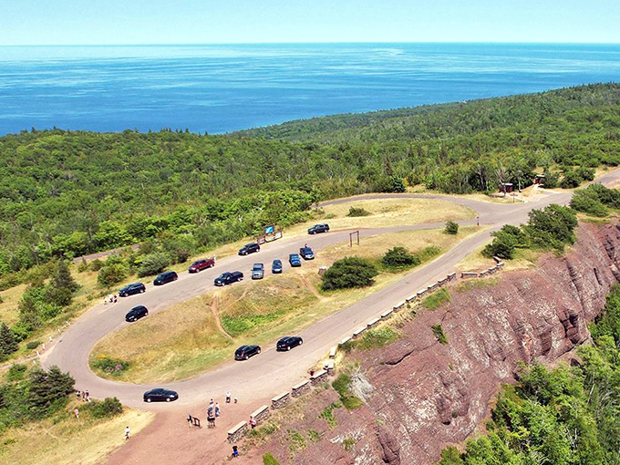 The cliff's edge reveals Lake Superior's sapphire expanse, where the water meets sky in a seamless blue embrace.