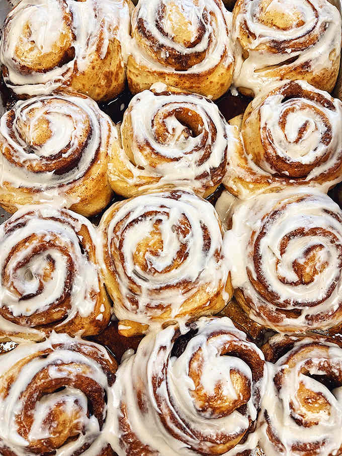 Fresh-baked cinnamon rolls glistening with cream cheese frosting, because sometimes you need something sweet to complement your morning coffee ritual.