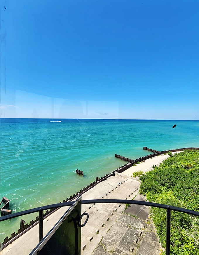 From the lighthouse balcony, Lake Michigan's turquoise waters stretch to meet the horizon in a seamless blend.
