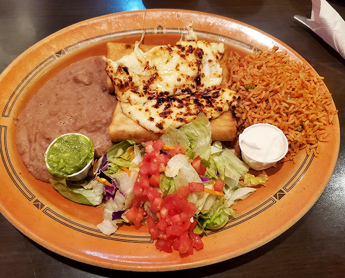 A plate that doesn't know the meaning of empty space&mdash;rice, beans, cheese-topped enchiladas, and fresh garnishes creating a fiesta of flavors.
