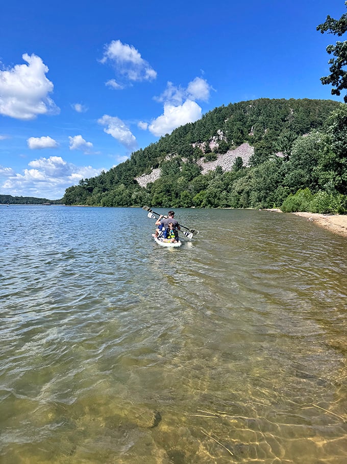 Adventure calls on Devil's Lake's crystal waters, where kayakers paddle beneath towering bluffs in perfect serenity.