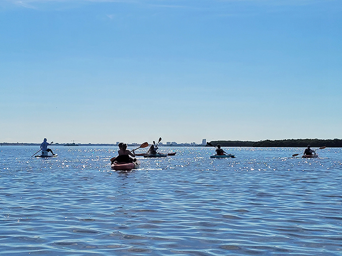Kayakers glide across mirror-like waters, creating gentle ripples in this liquid playground where time seems wonderfully suspended.