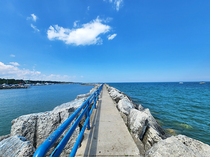 The harbor's breakwall stretches toward the horizon like a concrete invitation to adventure, complete with that perfect blue railing for Instagram moments.