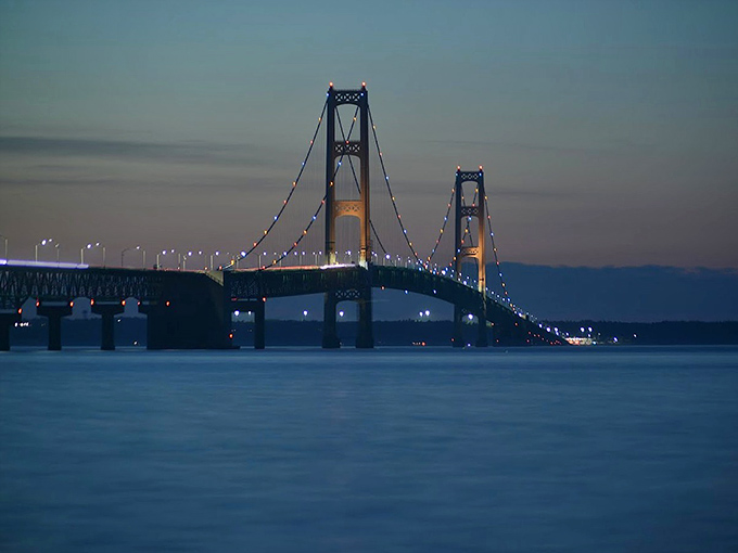 As twilight falls, the bridge's lights begin their nightly dance, transforming the engineering marvel into a five-mile string of pearls.