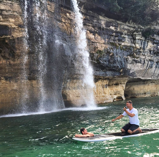 Adventure seekers paddle near the base of towering sandstone cliffs, gaining a perspective that land-lubbers can only dream about.
