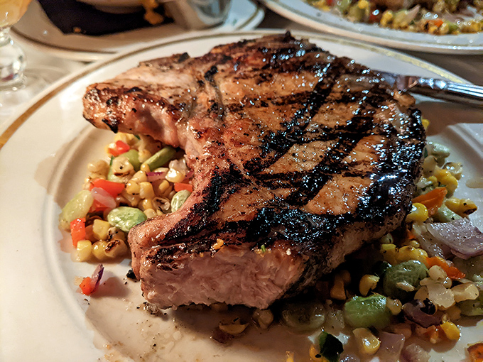 This pork chop doesn't just sit on the plate – it commands it, with grill marks as precise as pinstripes on a banker's suit.