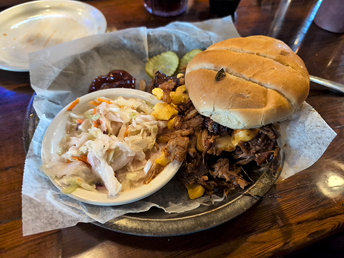 A pulled pork sandwich that demands two hands and your full attention, paired with creamy coleslaw for the perfect bite.