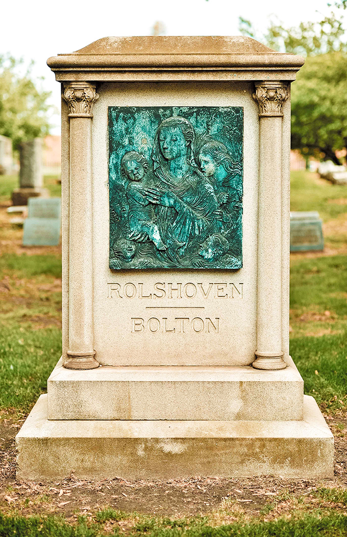 The Rolshoven-Bolton marker showcases exquisite craftsmanship with its patinated bronze relief depicting maternal tenderness transcending time.