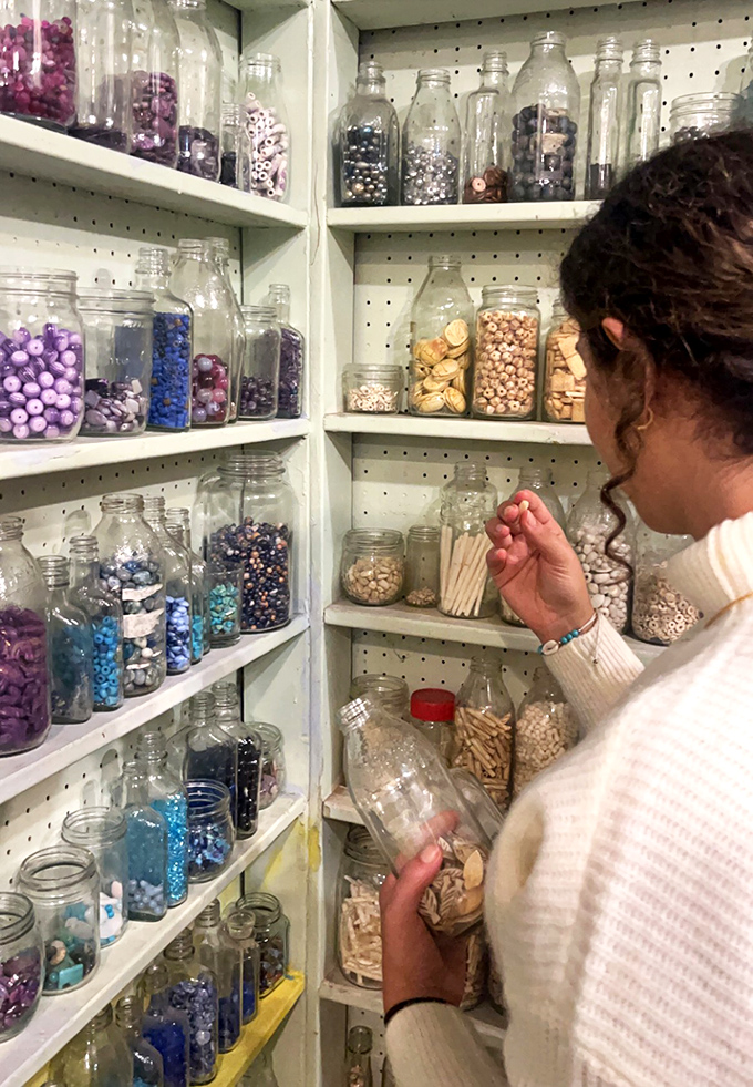 A visitor carefully selects from glass jars filled with tiny treasures &ndash; each bead a potential component in their own wearable story.