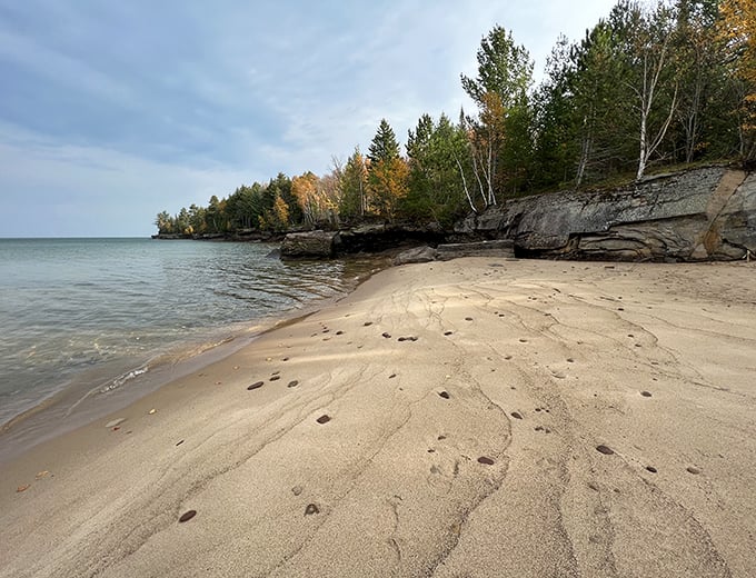 Rocky outcroppings meet golden sand at this secluded stretch of shoreline, creating nature's perfect contrast of textures.