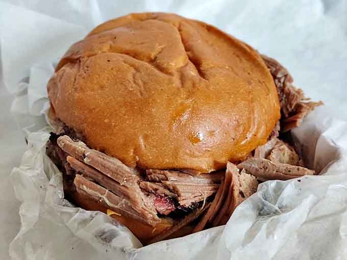 A mountain of tender brisket nestled in a soft bun creates a sandwich that requires both hands and at least three napkins.