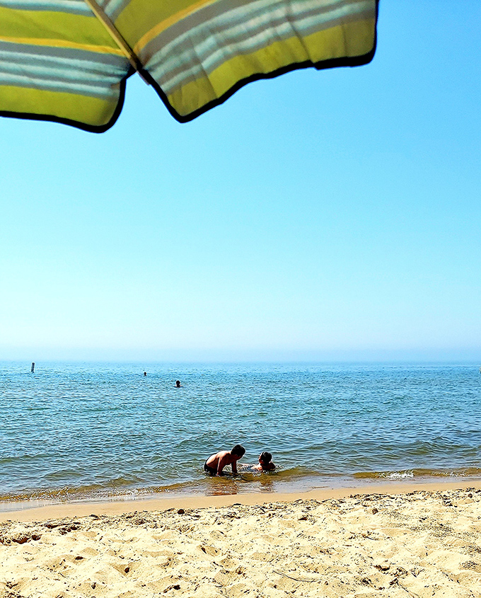 Children discover the simple joy of cool lake waters on hot summer days, their laughter carrying across Grand Haven's shoreline.