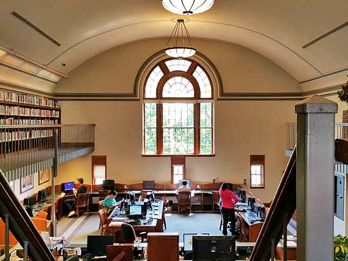 The two-story reading room transforms research into a sacred experience, with natural light streaming through arched windows onto eager learners below.